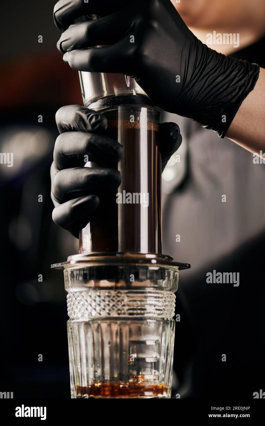 partial view of barista pressing coffee in aero press while preparing ...