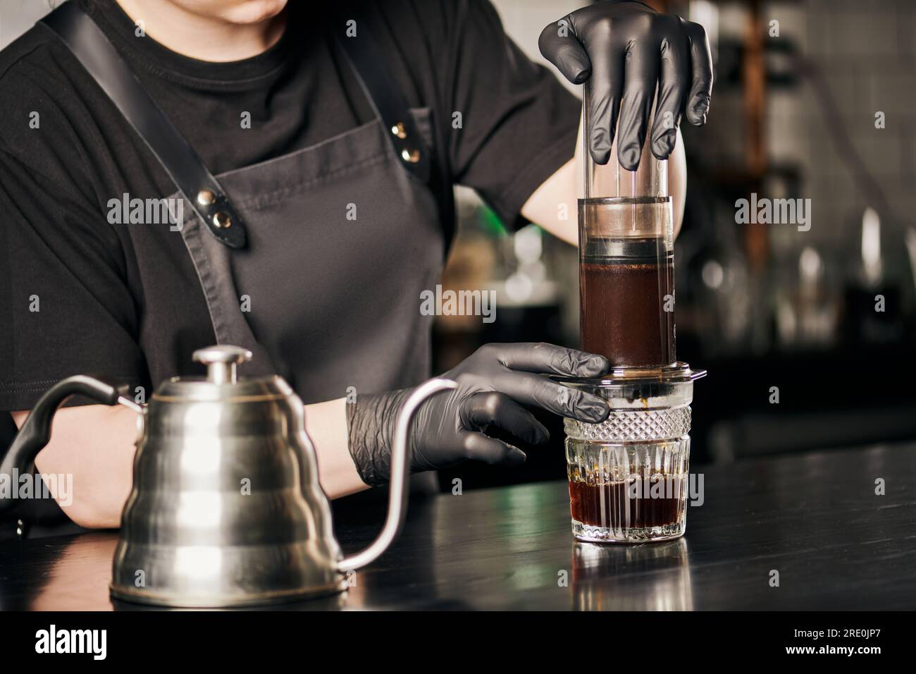 partial view of barista in black gloves and apron preparing espresso in ...