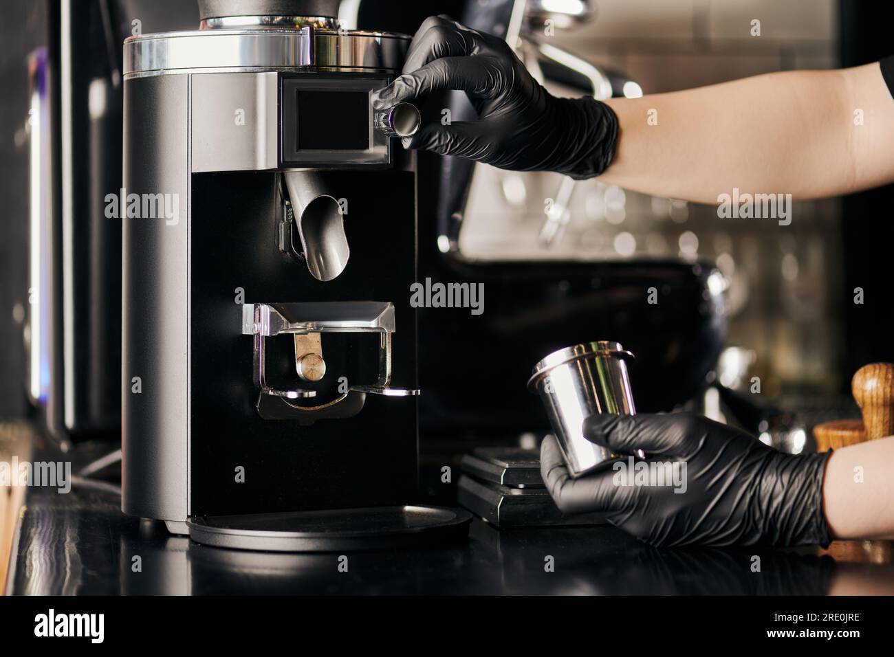 barista in black latex gloves operating electric coffee grinder and ...