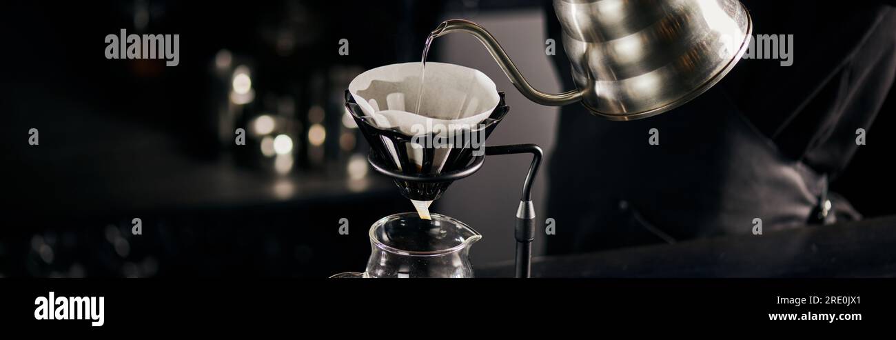 barista pouring boiling water into coffee filter on dripper stand above ...