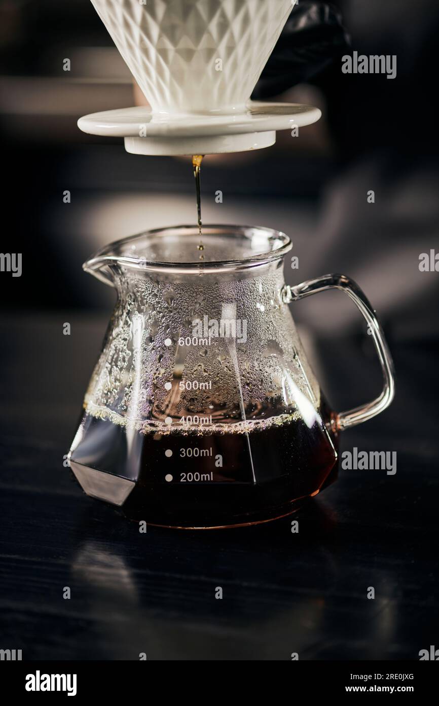 freshly brewed espresso dripping into glass pot from ceramic dripper, V ...