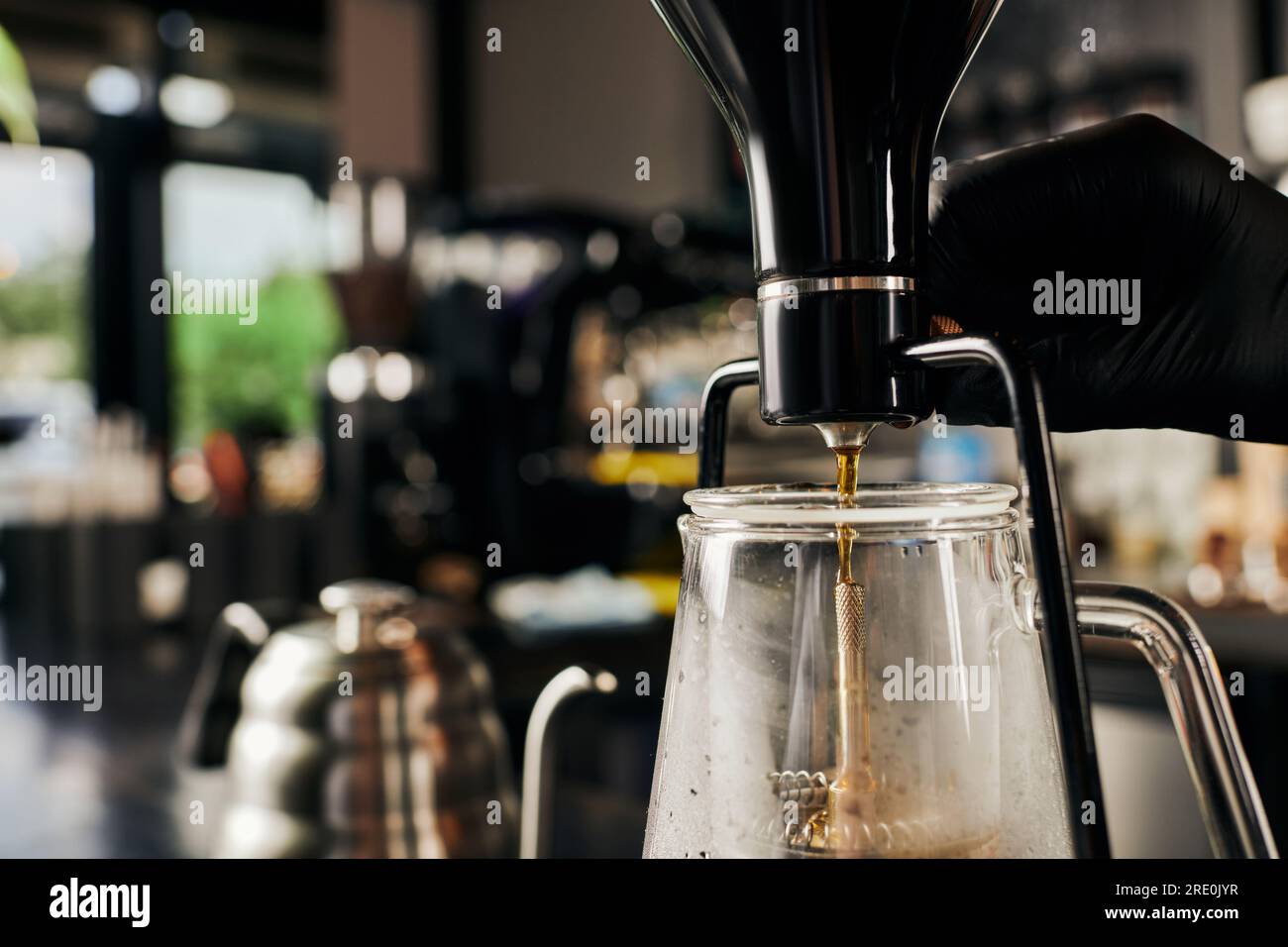 partial view of barista regulating siphon coffee maker while brewing ...