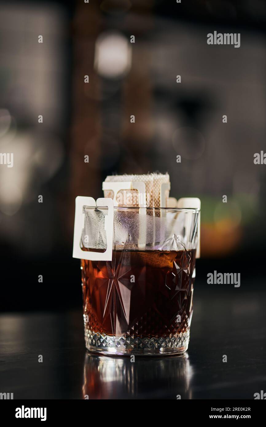 glass with ground coffee in paper filter bag on black counter, aromatic ...