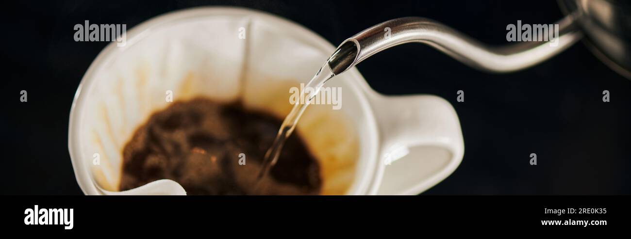 boiling water pouring from kettle into ceramic dripper with coffee in ...