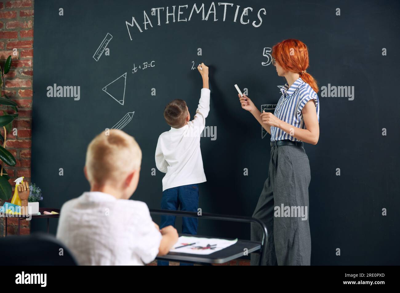 Little bot, child, student standing at chalkboard, writing and solving ...