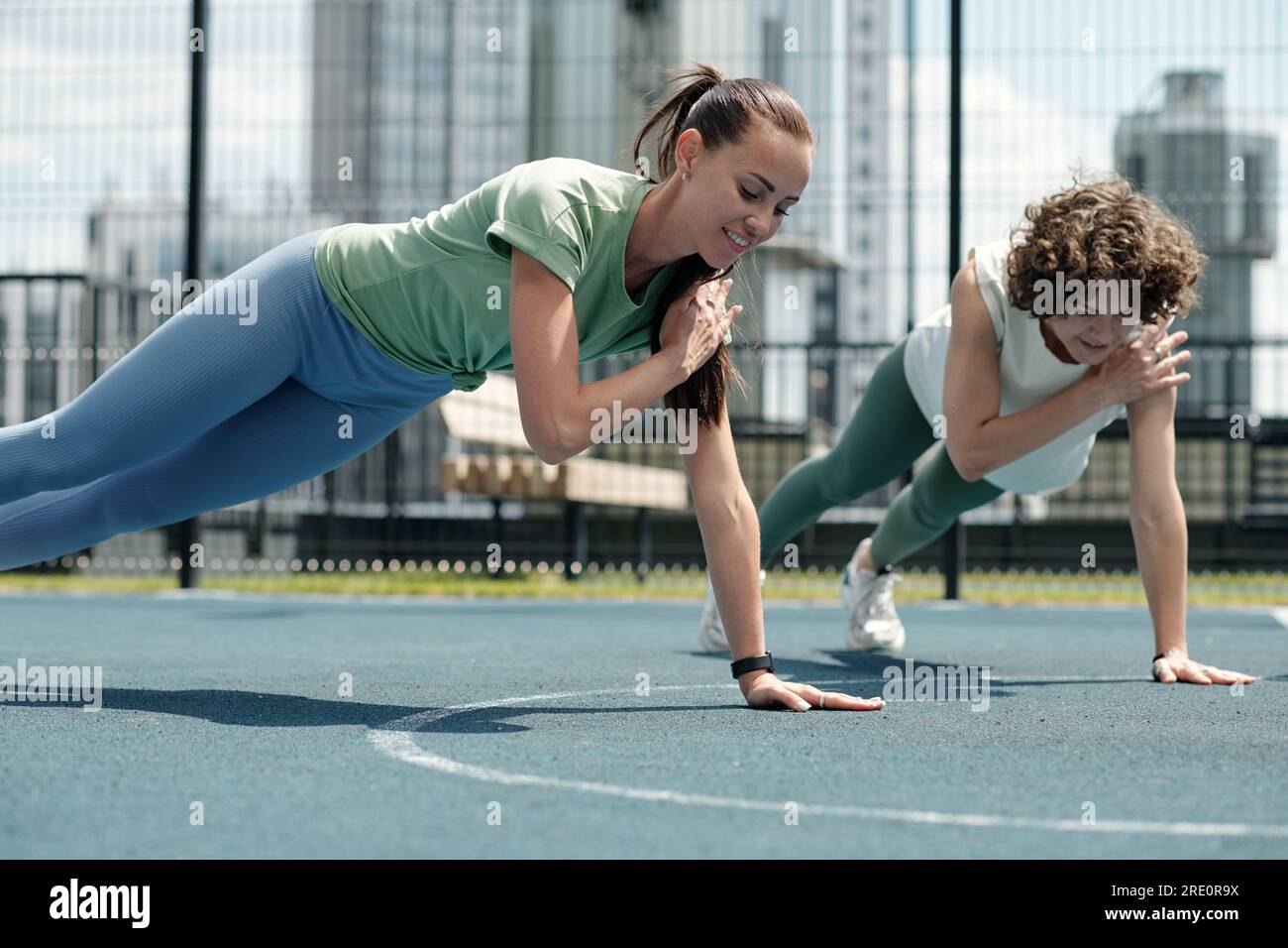 Two young active female athletes doing difficult physical exercise on ...