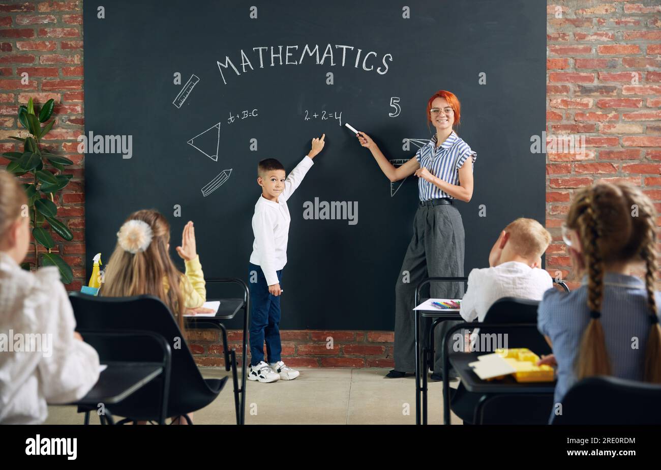 Little bot, child, student standing at chalkboard, writing and solving ...