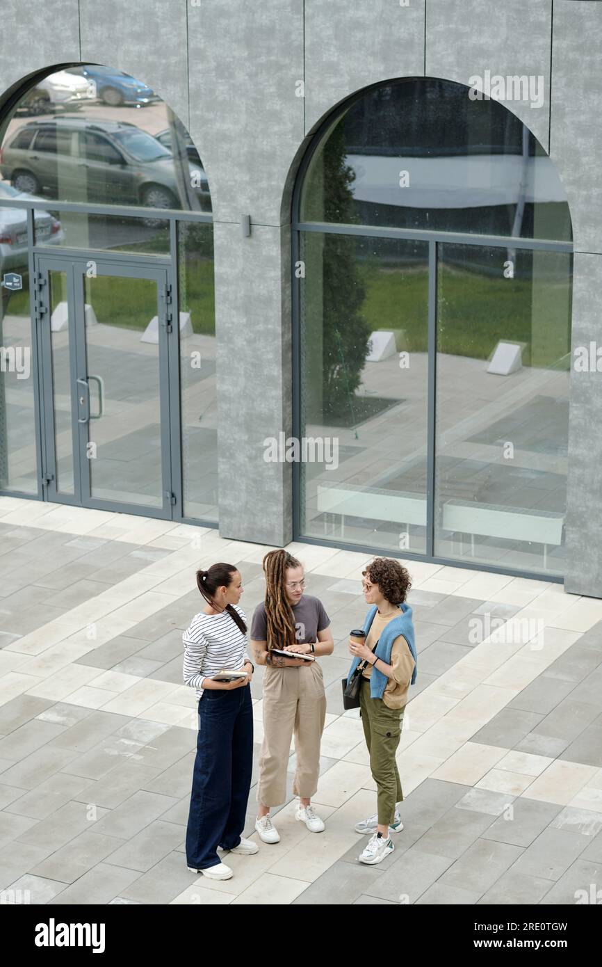 Long shot of three young businesswomen in casualwear having discussion ...