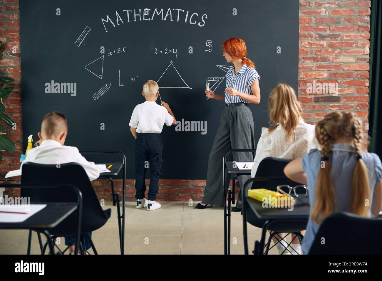 classroom with kids learning geometry. Little boy standing by ...