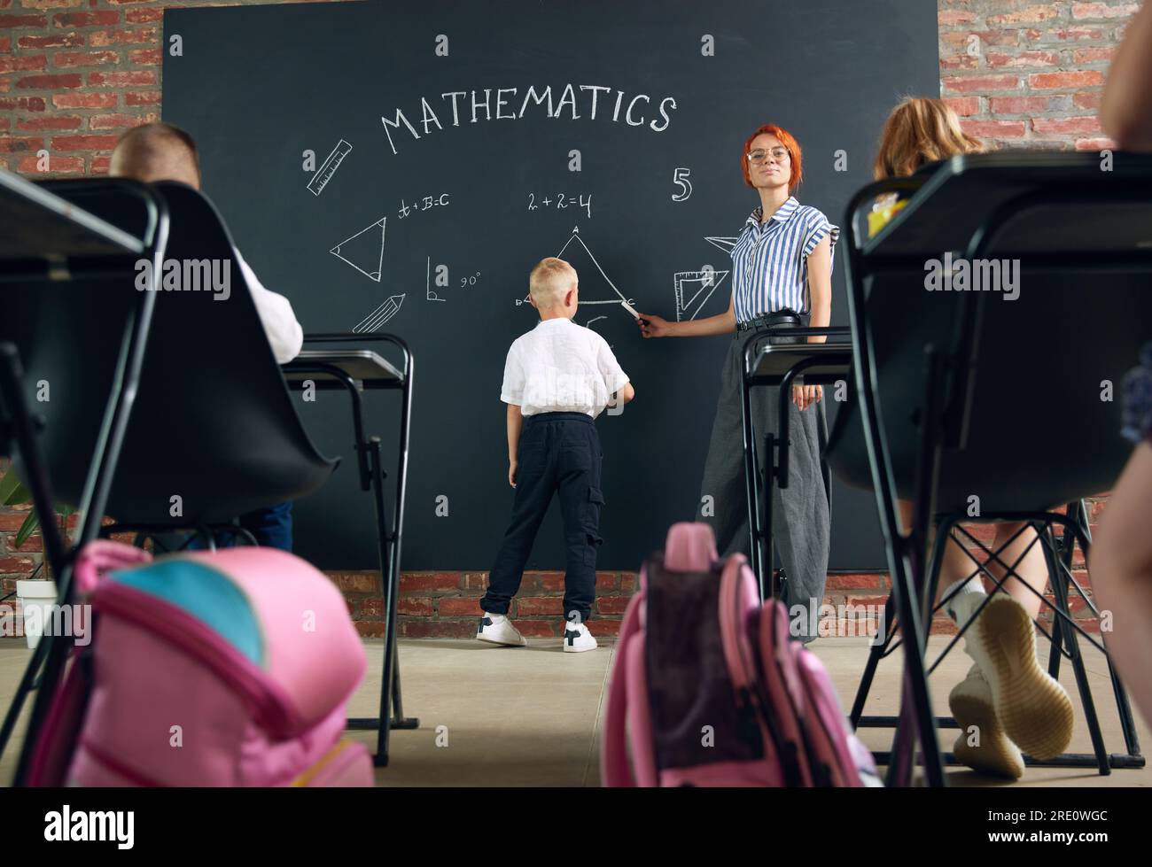 classroom with kids learning geometry. Little boy standing by ...