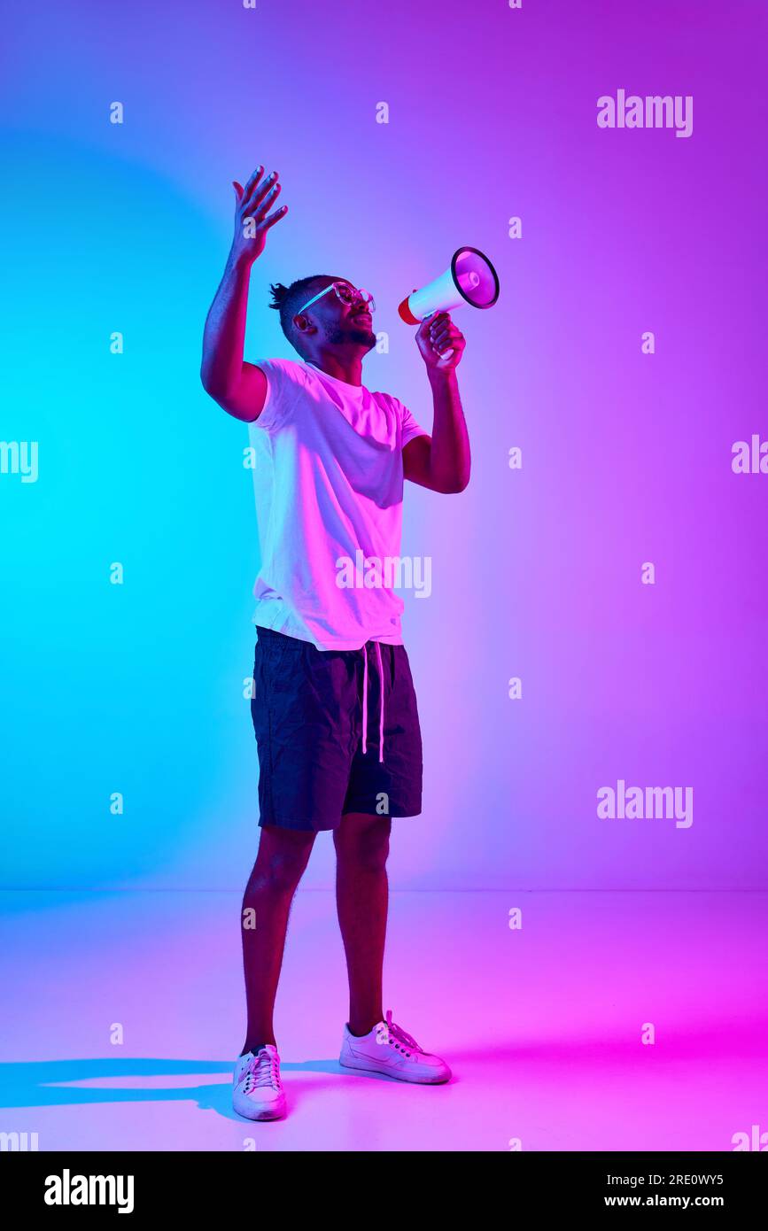 Full length questioning african man shouting in megaphone, looking up ...