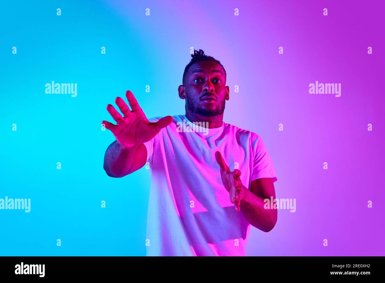 Frightened and withdraw african man looking at camera over colorful ...