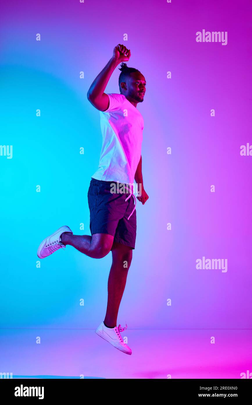Full body shoot of jumping on one leg african man looking away over ...