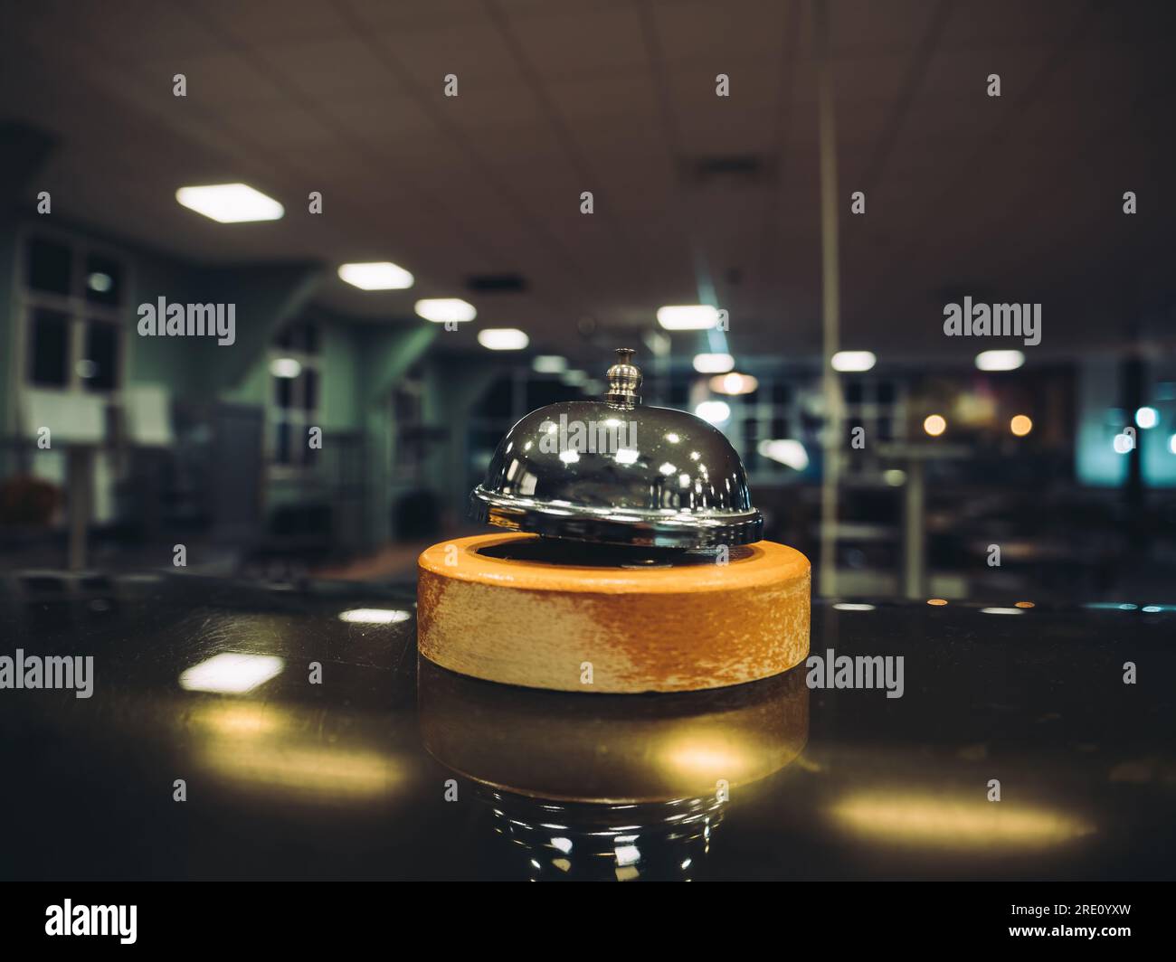 A bright bell on a silver desk in a hotel lobby, signaling assistance ...
