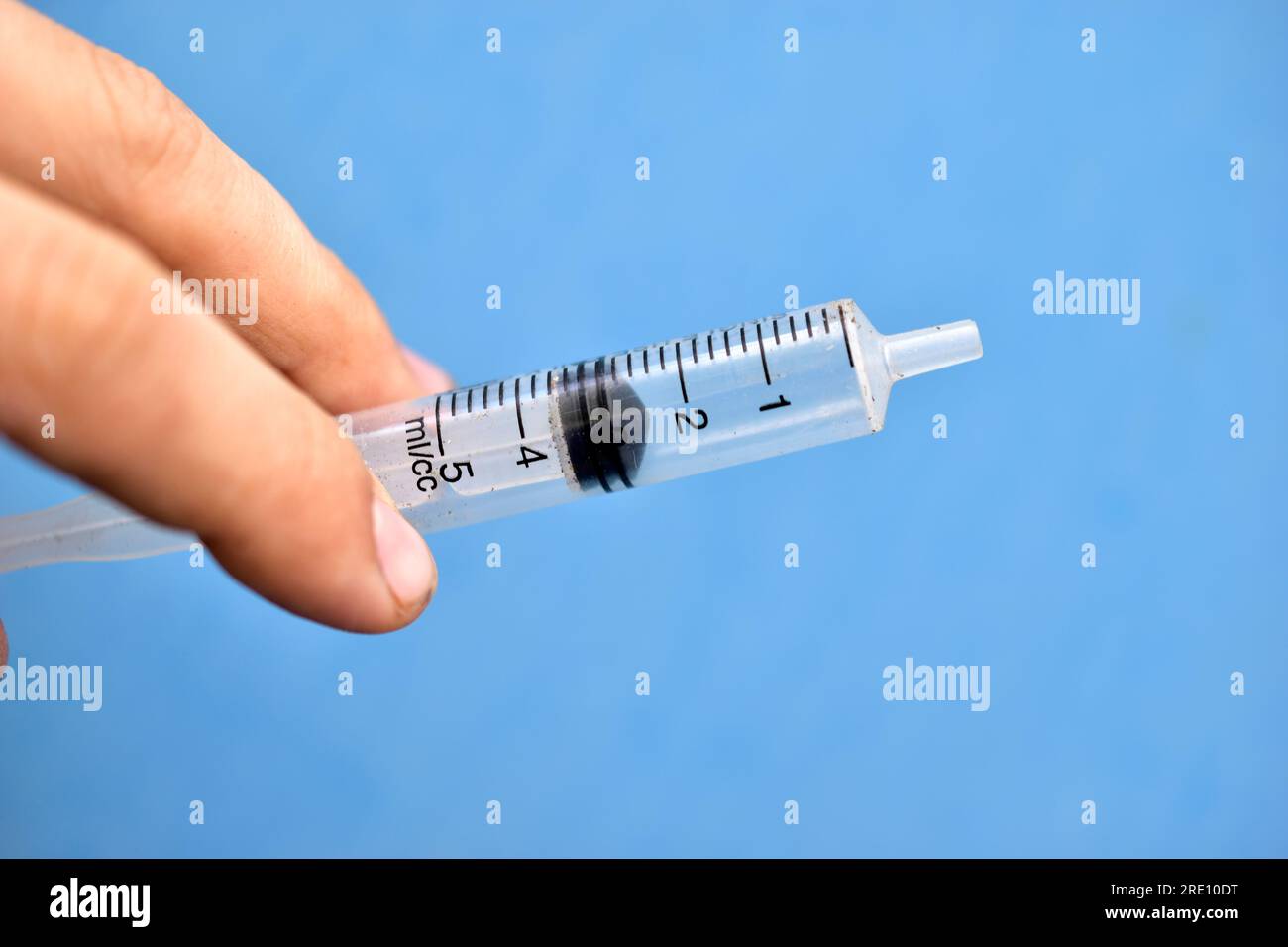 Empty plastic syringe with no needle in hand on a blue background Stock ...