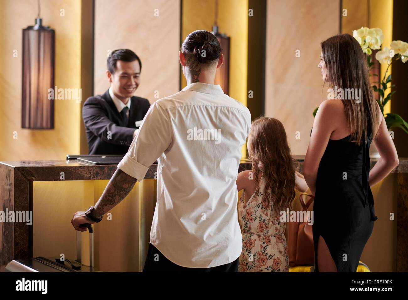 Family standing at hotel reception, view from back Stock Photo - Alamy