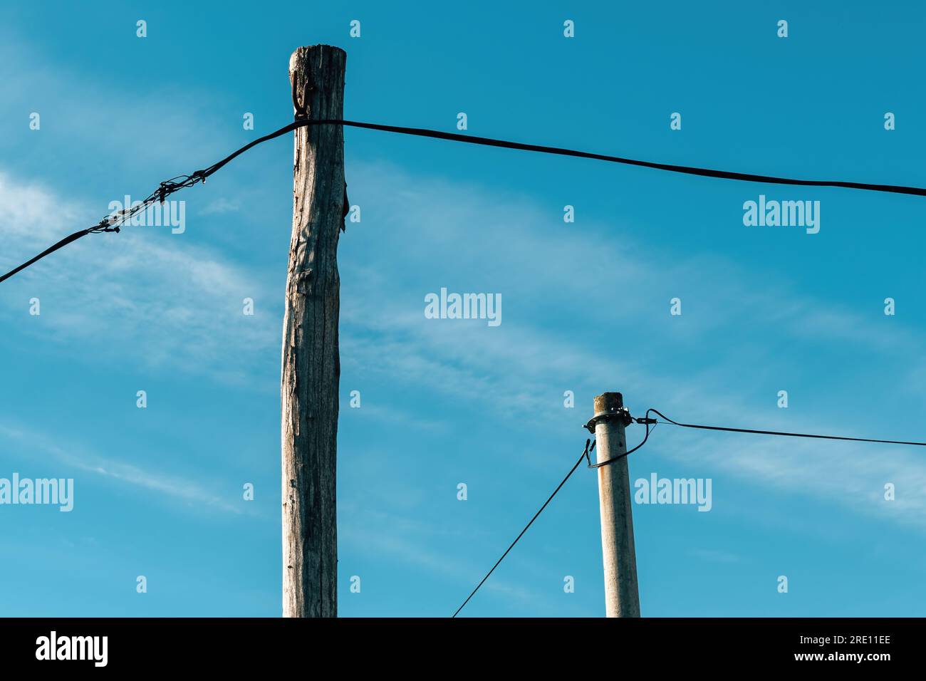 Two electricity poles, a wooden and a concrete one with electrical ...