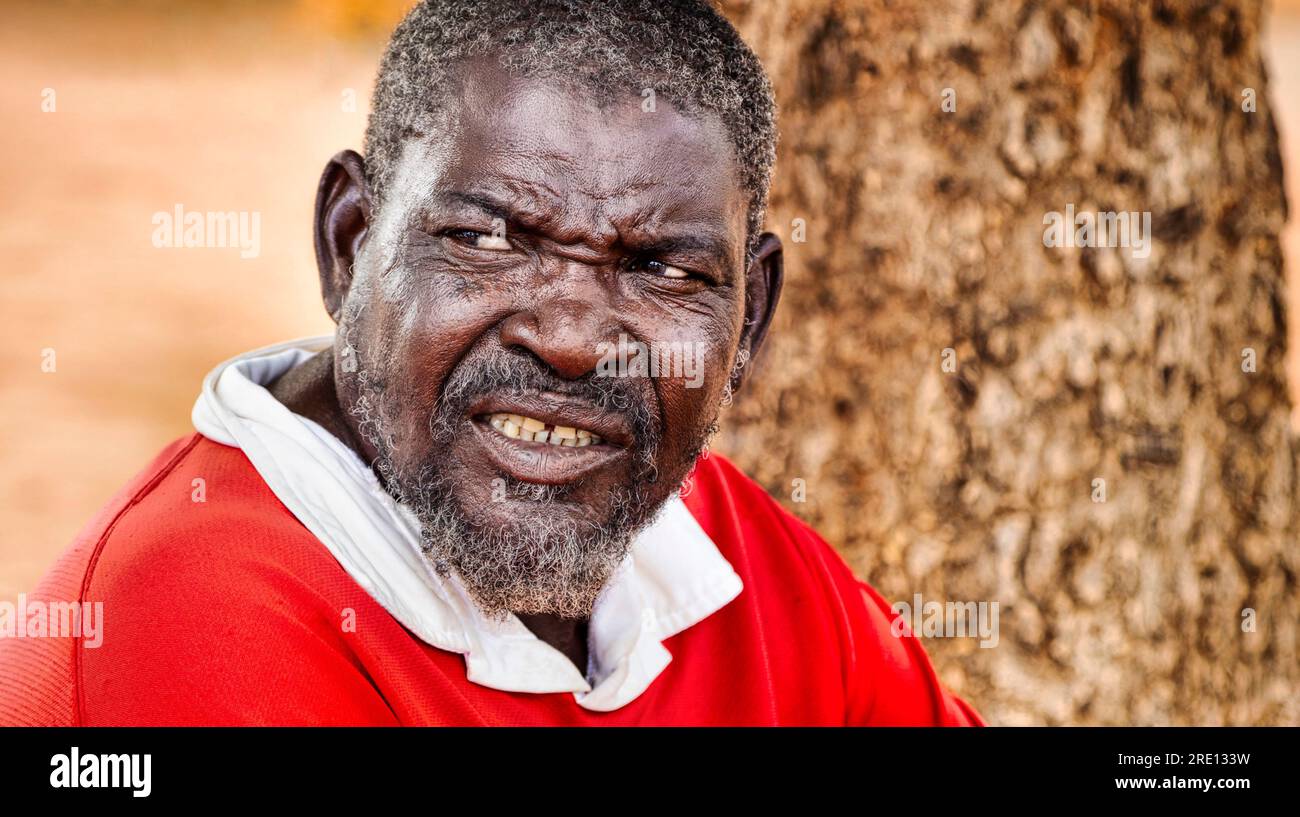 portrait of old man with red shirt in the yard, botswana village ...