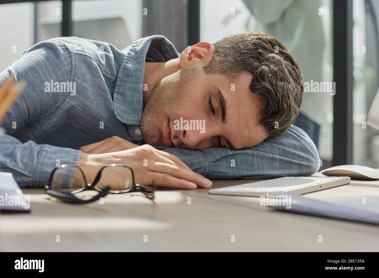 Tired businessman sleeping on his desk in front of laptop, overworking ...