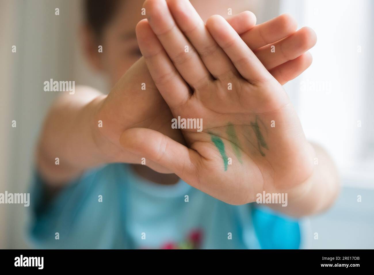Boy hiding his face and showing his hands after doing painting ...