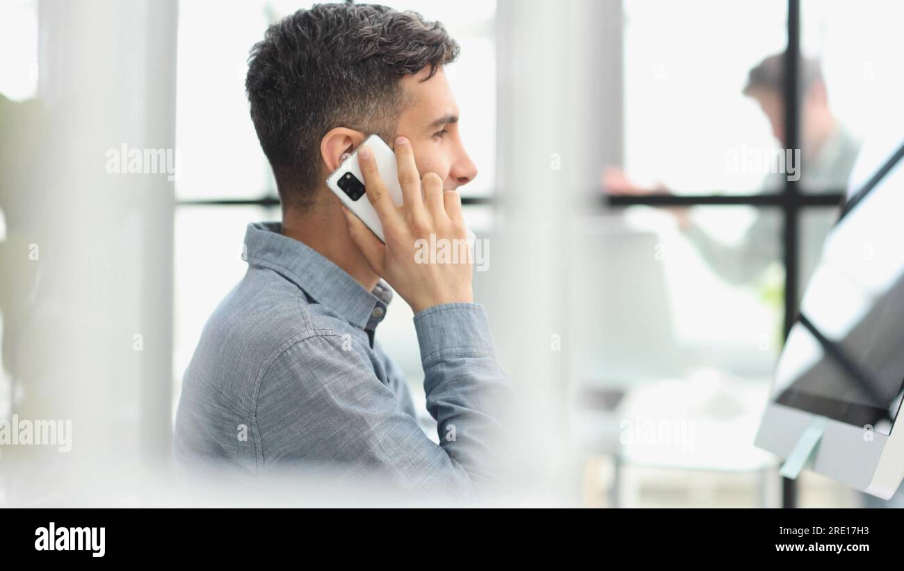 Portrait of young entrepreneur in casual office making phone call while ...