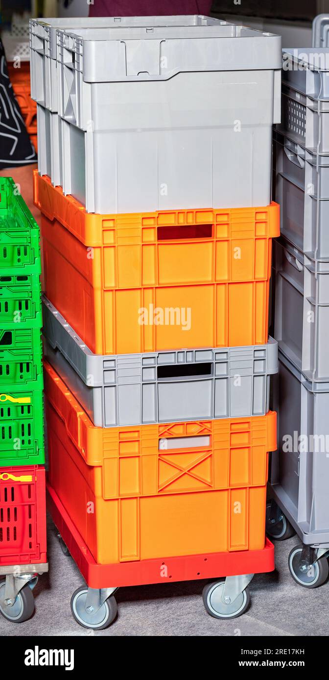 Gray, orange, green and red plastic containers are stacked on top of ...