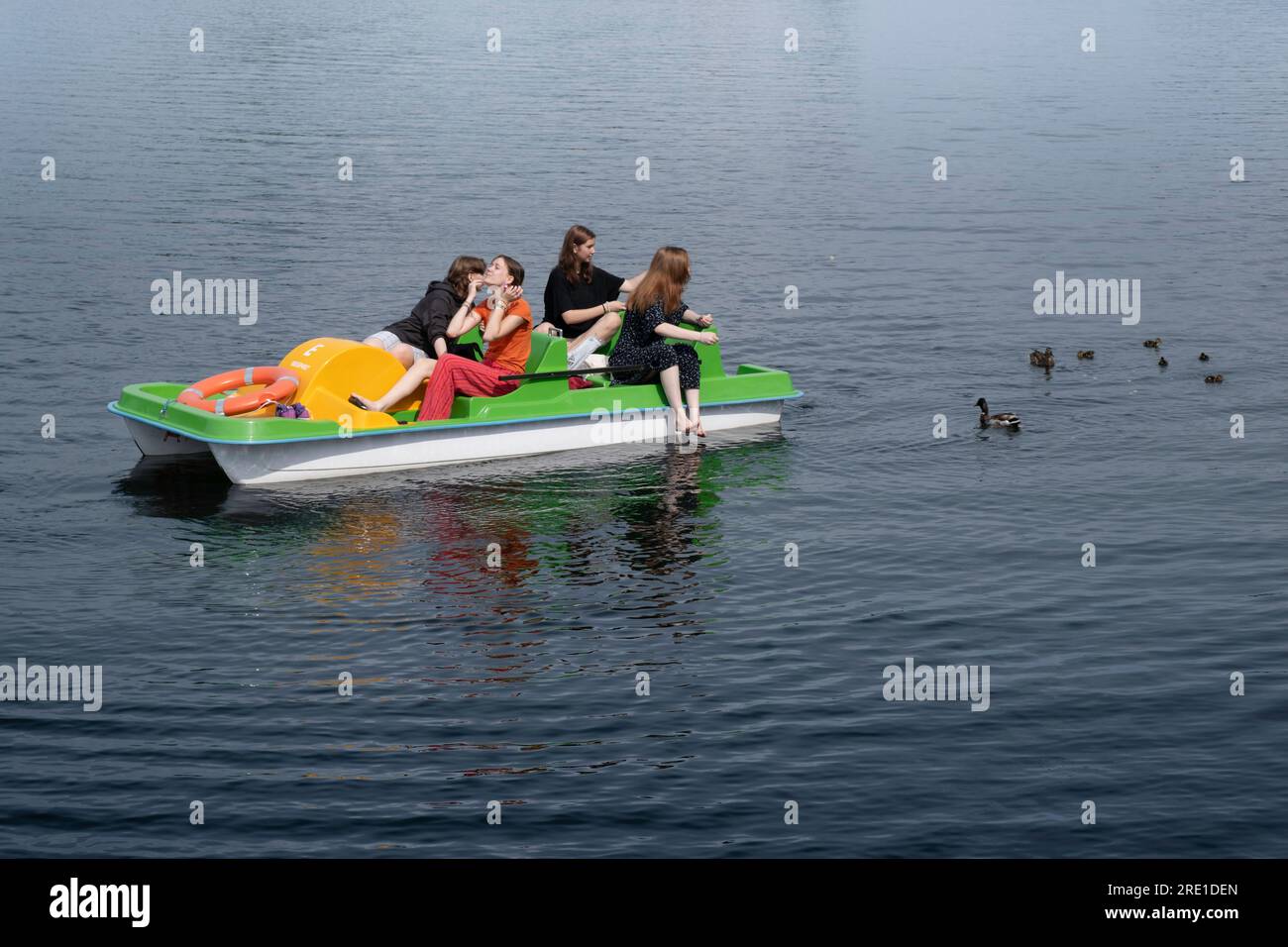 Cute girls have fun in a pedal boat. They feed the ducks and enjoy the ...