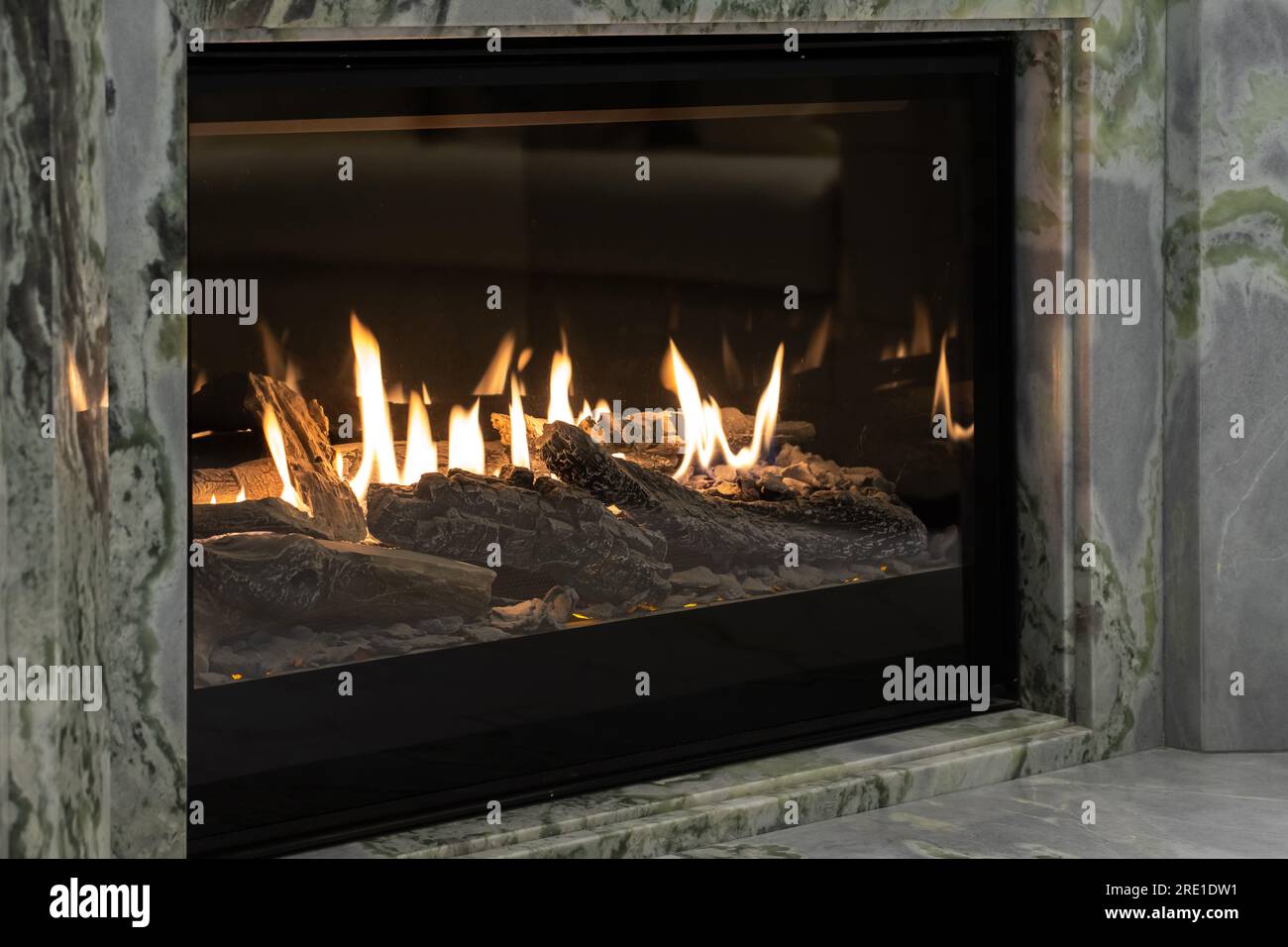 Burning modern gas fireplace built into marble Stock Photo - Alamy