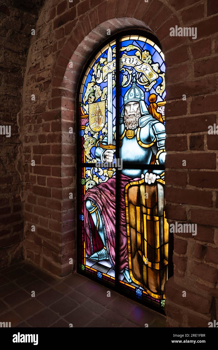 Colorful stained glass window with an image of a seated knight with ...
