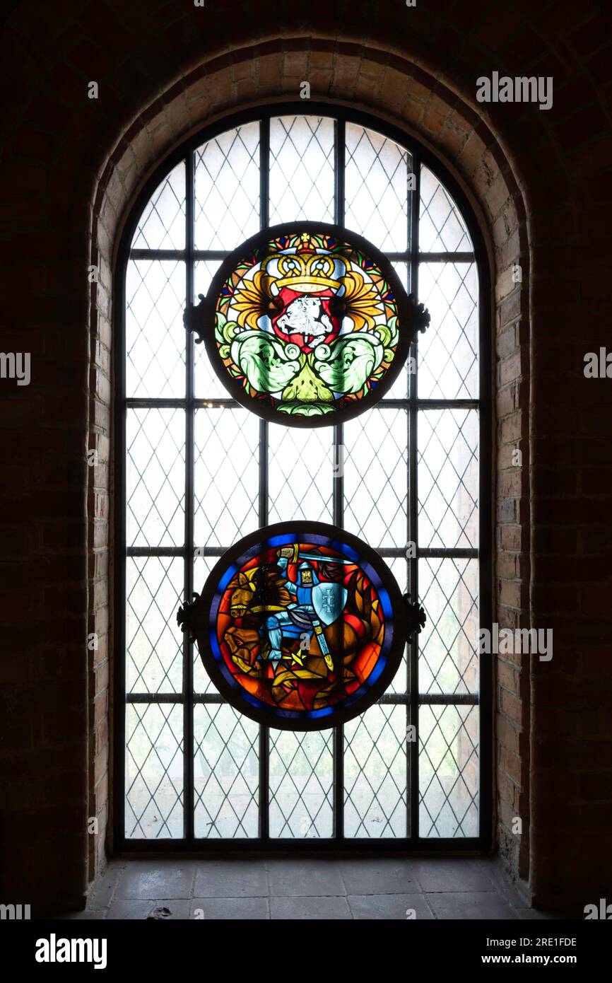 Arched window in castle wall with two round stained glass windows in ...