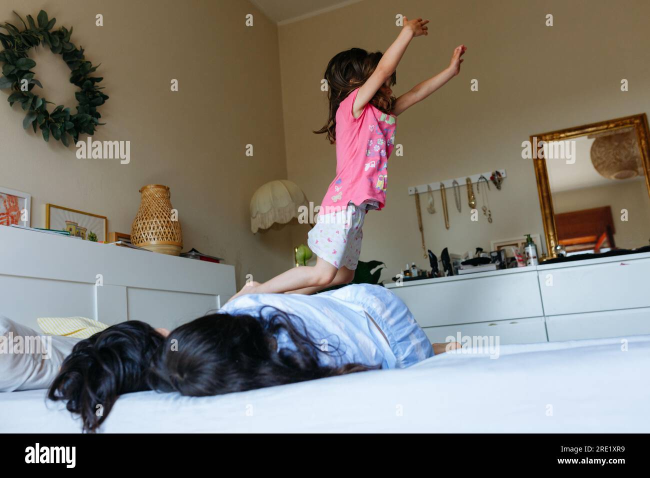 two children lying on the bed and other child jumping over Stock Photo ...