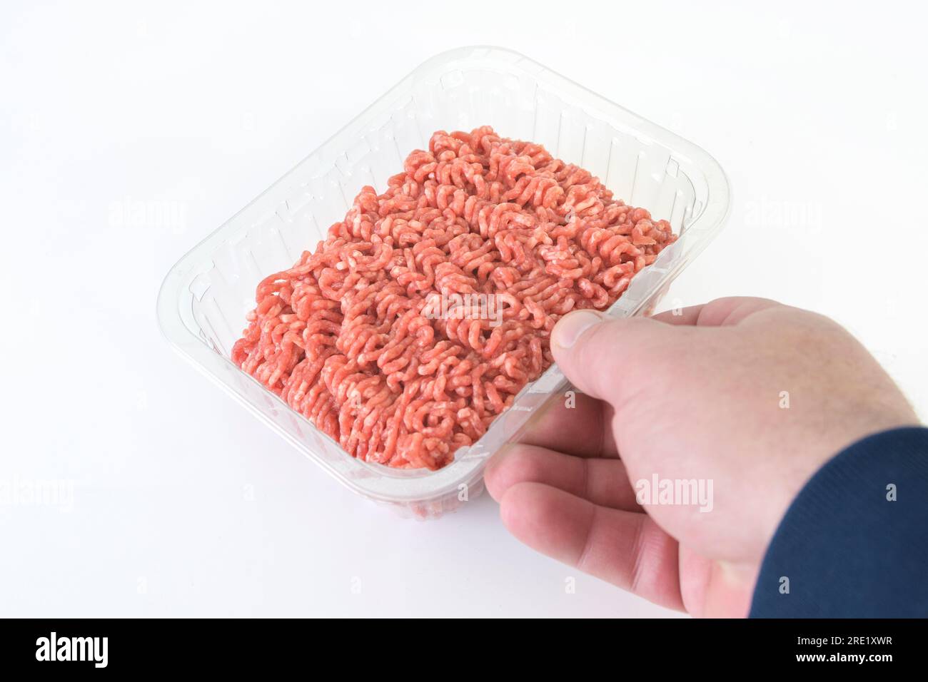Hand holding ground beef in store-bought plastic transparent packaging ...
