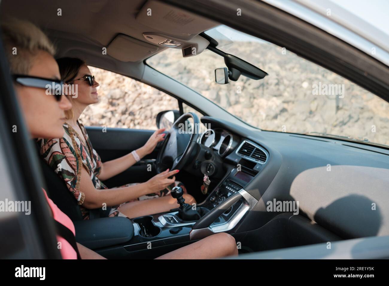 Two young friends singing and dancing as they drive to the beach ...