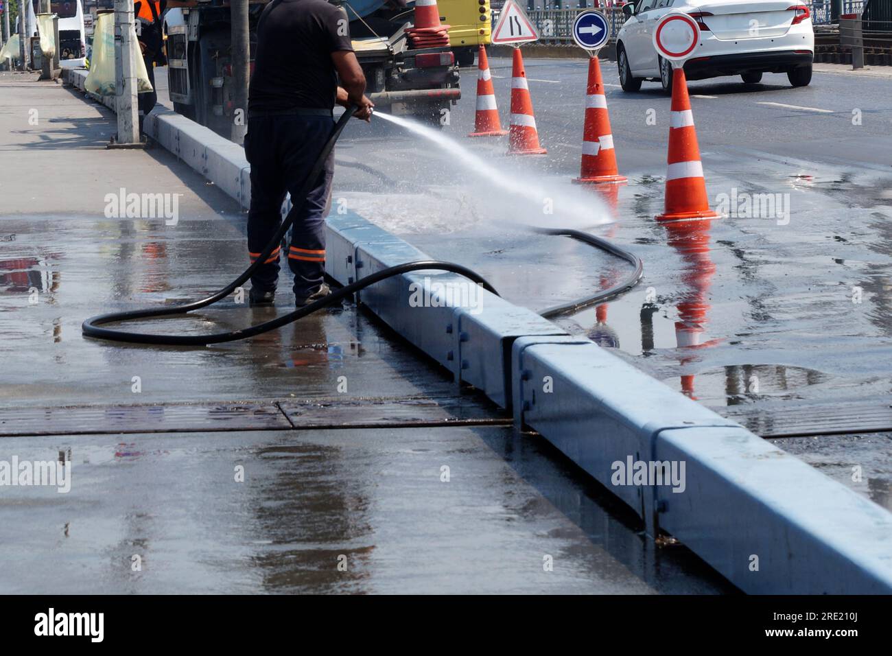 road worker washing the roadway with water from a hose Stock Photo - Alamy
