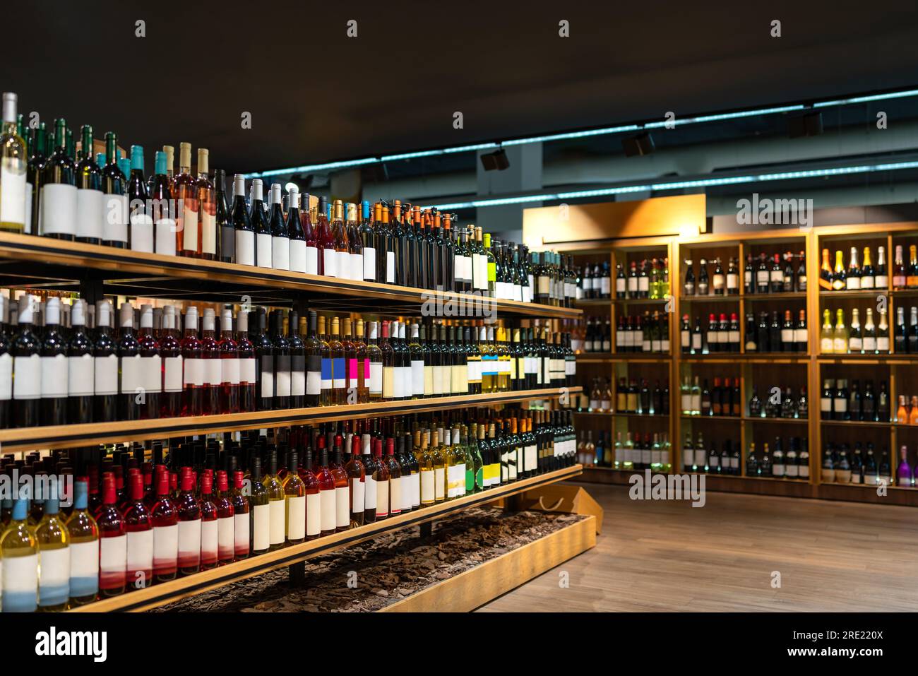 Wine bottles in a row on shelves in wine store, alcohol retail business ...