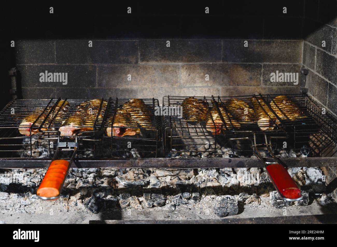 Fish is baked on a metal grill in a flame of fire. Barbecue cooking ...
