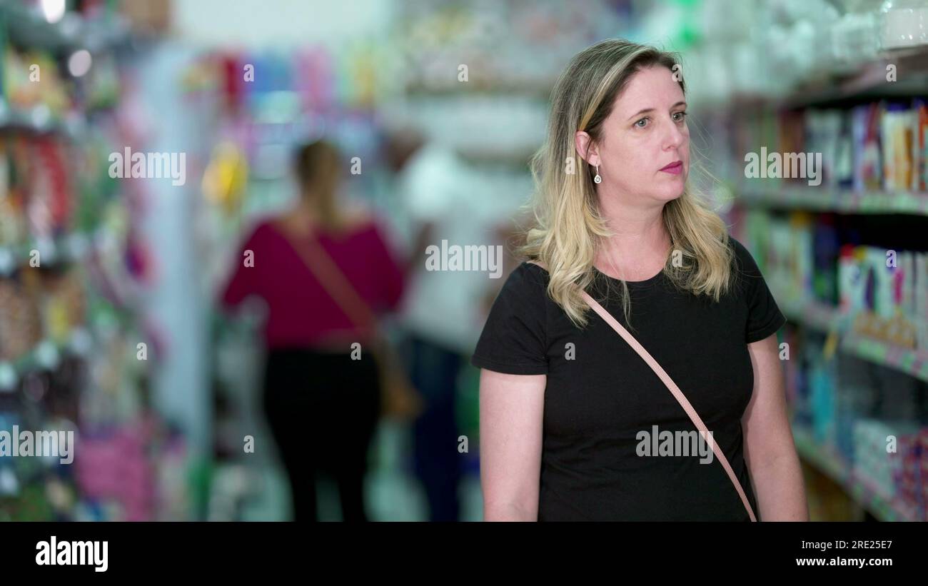Female shopper searching for product at grocery store aisle, consumer ...