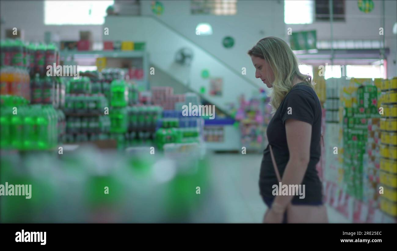 Female Shopper Pondering Purchase in Soda Drink Aisle of Supermarket ...