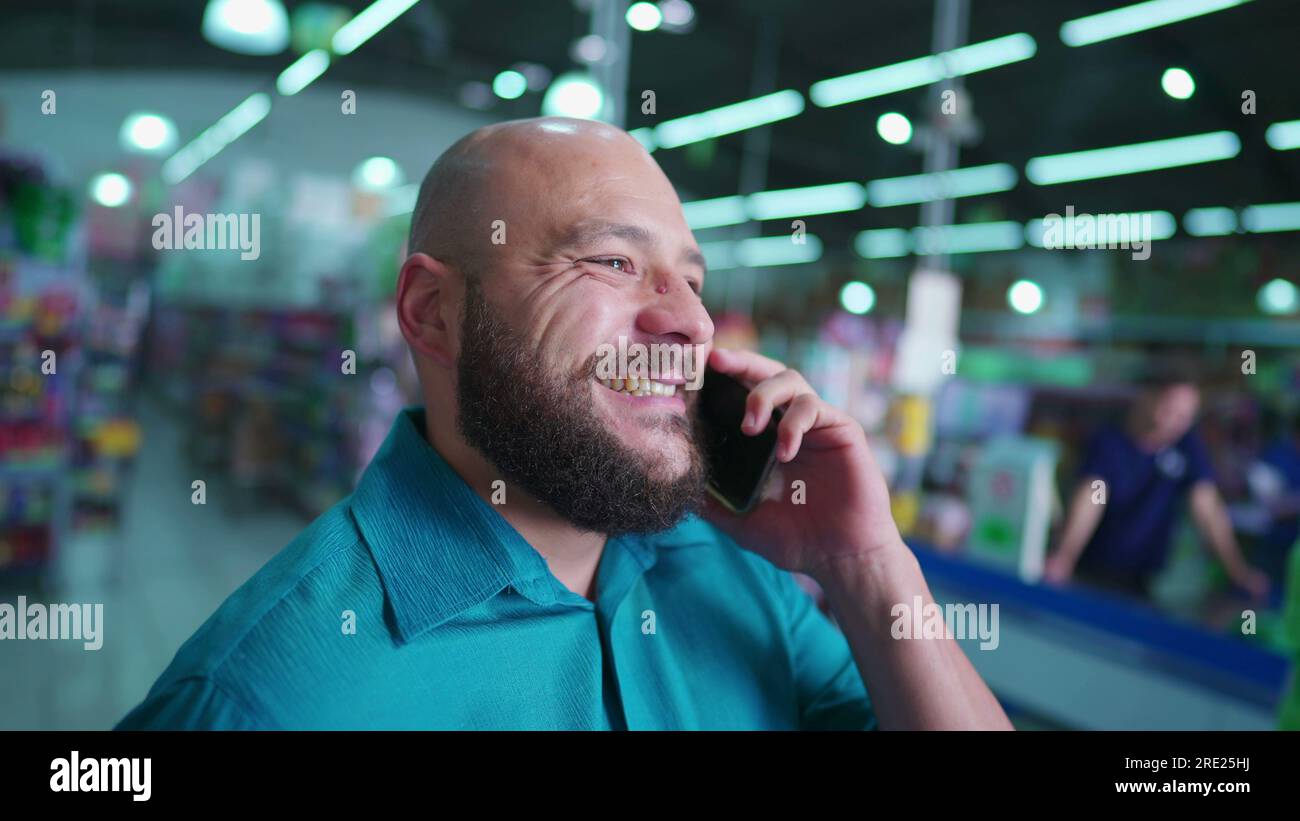 Happy casual Man speaking on phone inside store shed. South American ...