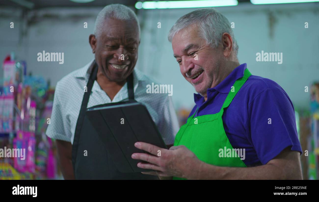 Diverse Senior Employees at Supermarket holding tablet device pointing ...