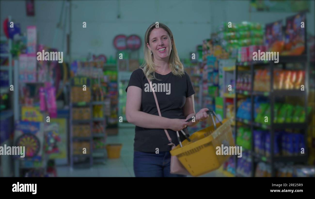 Female consumer smiling while standing inside Supermarket store holding ...
