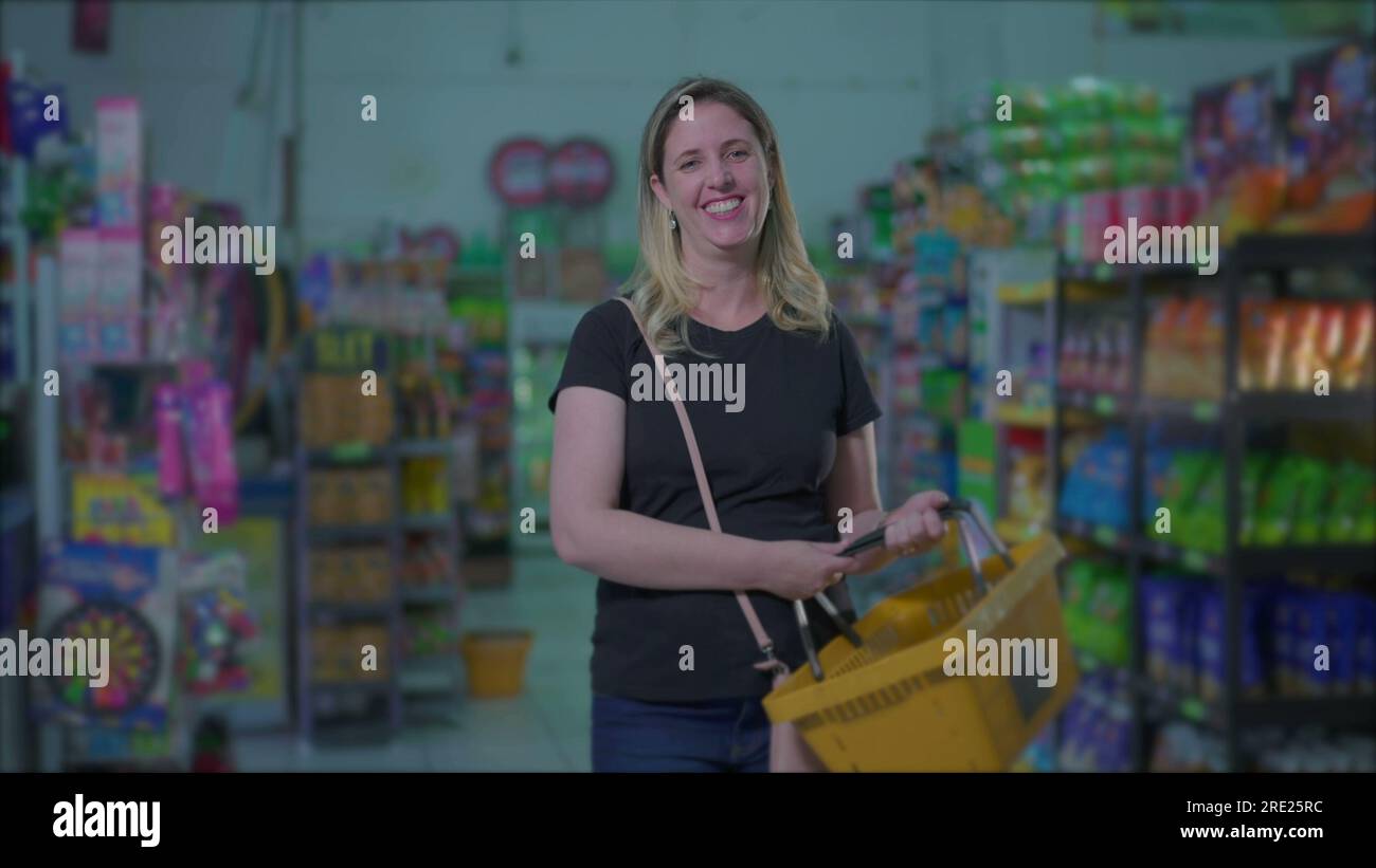 Female consumer smiling while standing inside Supermarket store holding ...