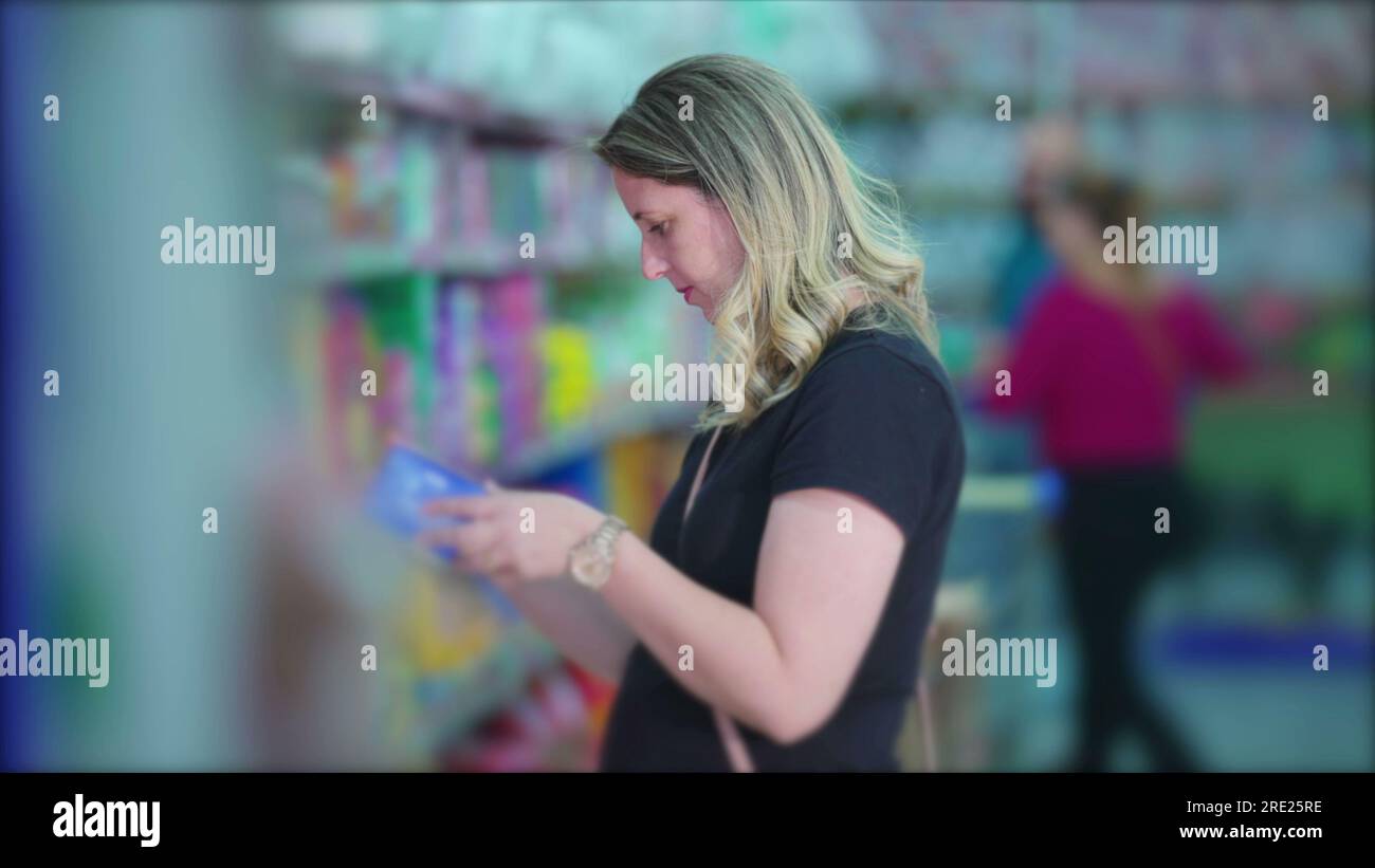 Female Customer Selecting Item from Grocery Shelf, Depicting Consumer ...