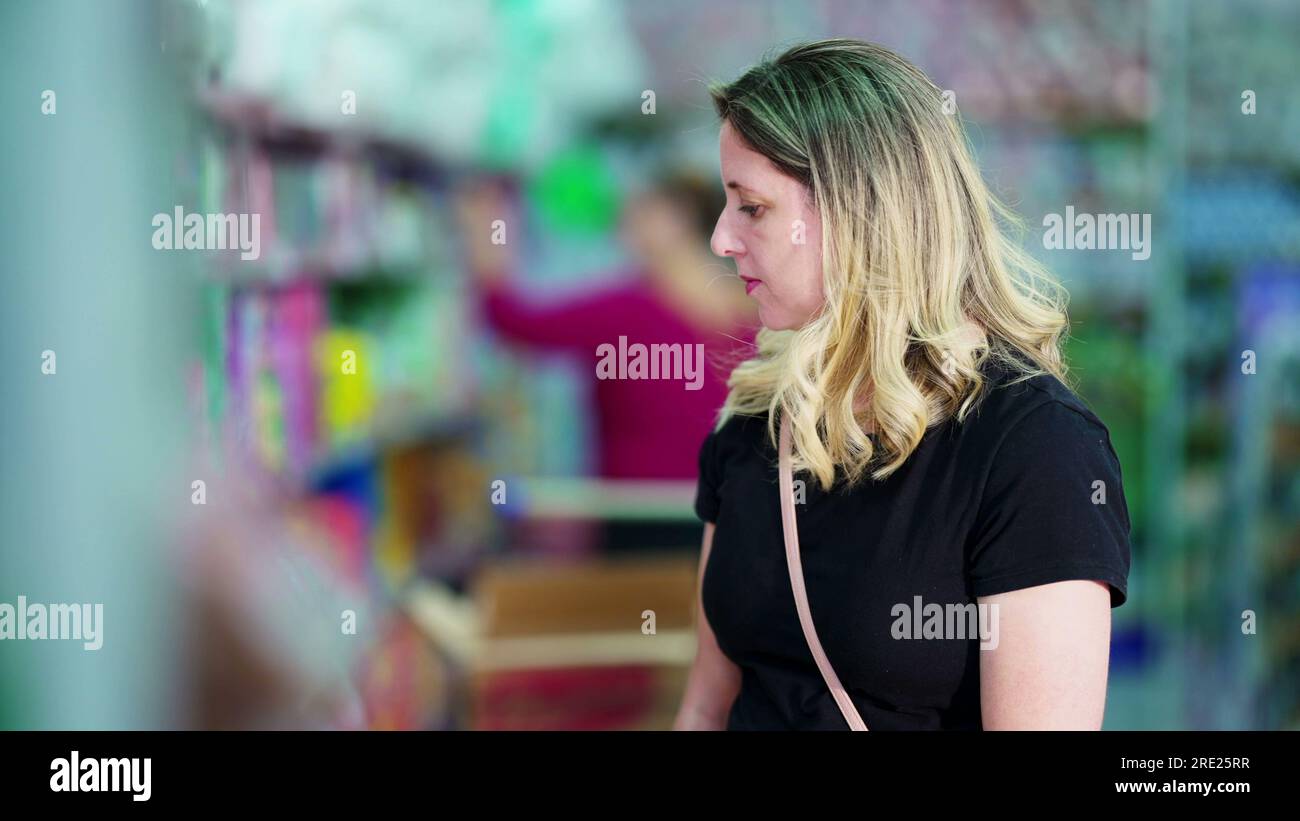 Female consumer looking for product at grocery store aisle. Candid ...