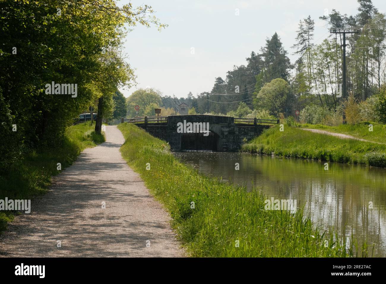 A picturesque gravel road runs parallel to a small canal under the ...
