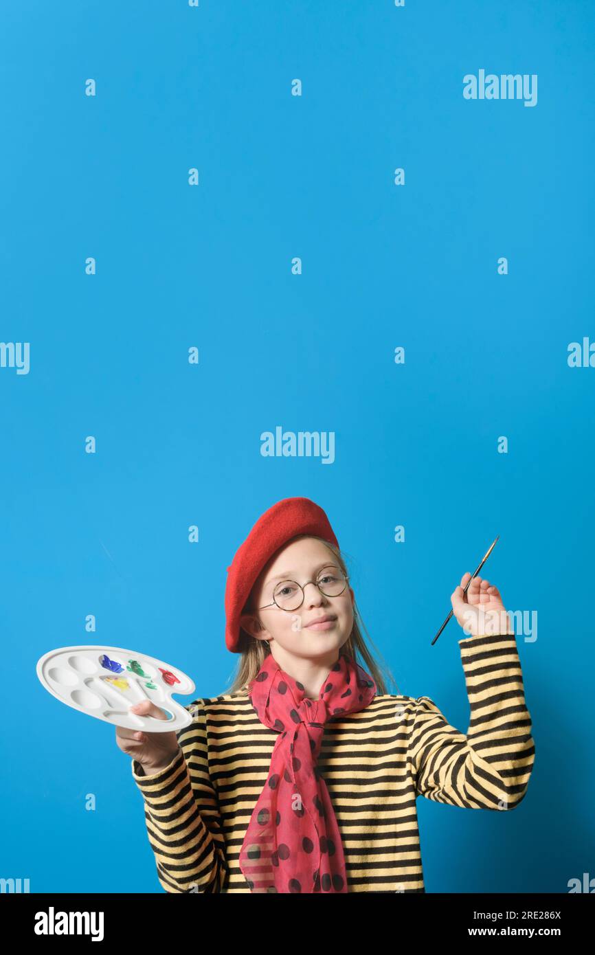 A young artist. A girl with a palette of colors in a bright red beret ...