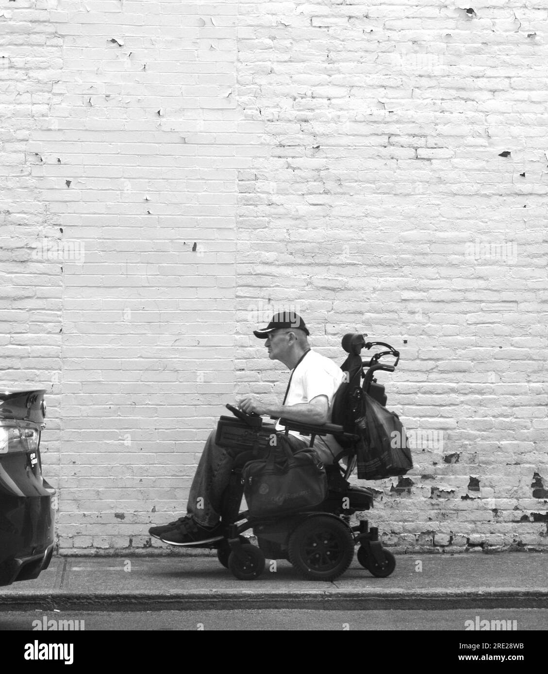 A man rides a battery-powered electric power chair or wheelchair along ...