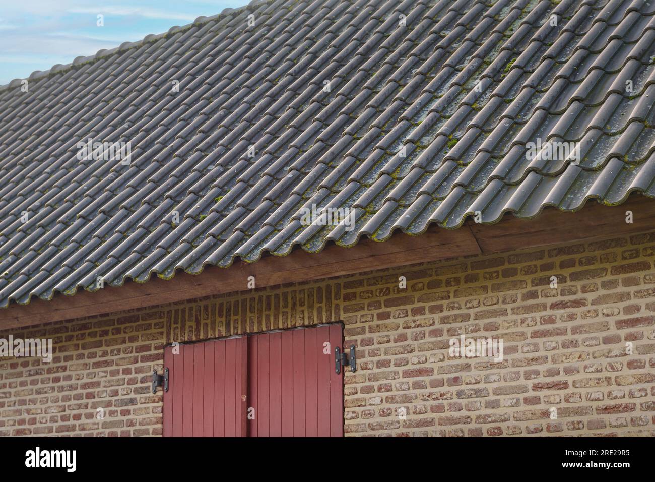 The roof of an old tiled building. Fragment of brickwork and window ...