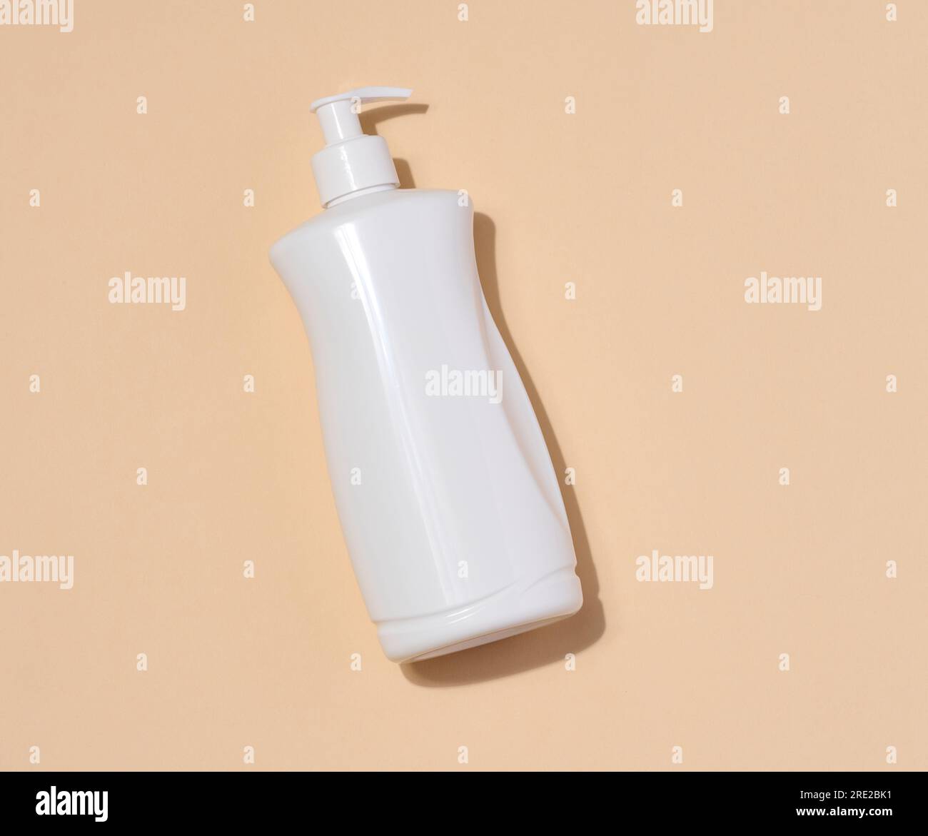 White plastic container with a pump for liquid products on a beige ...