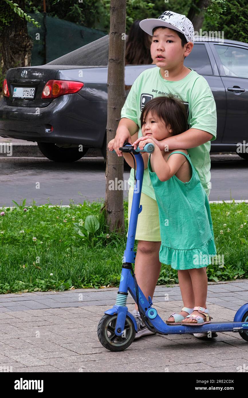 Kazakhstan, Almaty. Boy and Little Sister on Scooter on the Panfilov ...